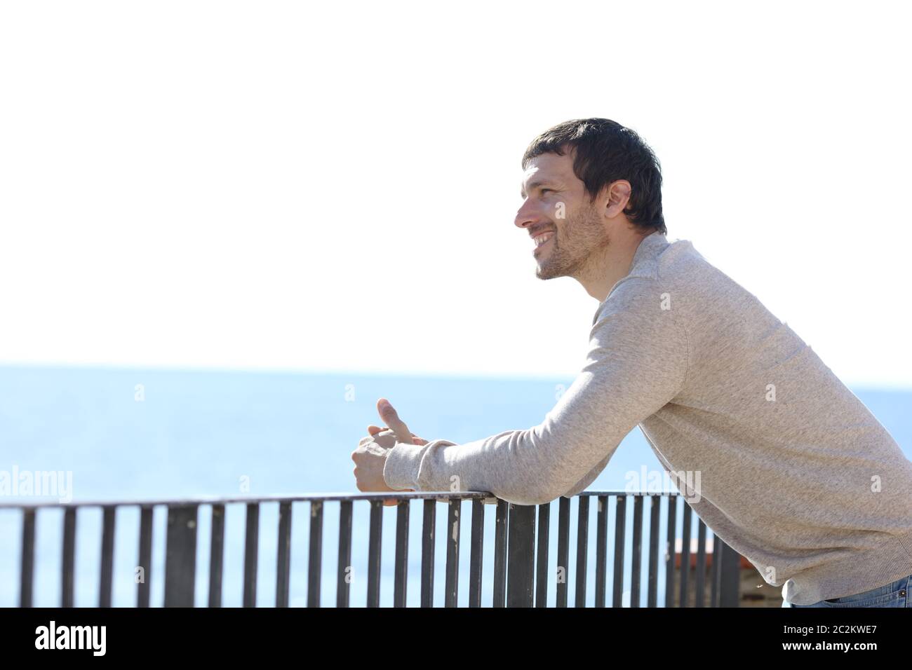 Side view portrait of a happy man contemplating views from a balcony on ...
