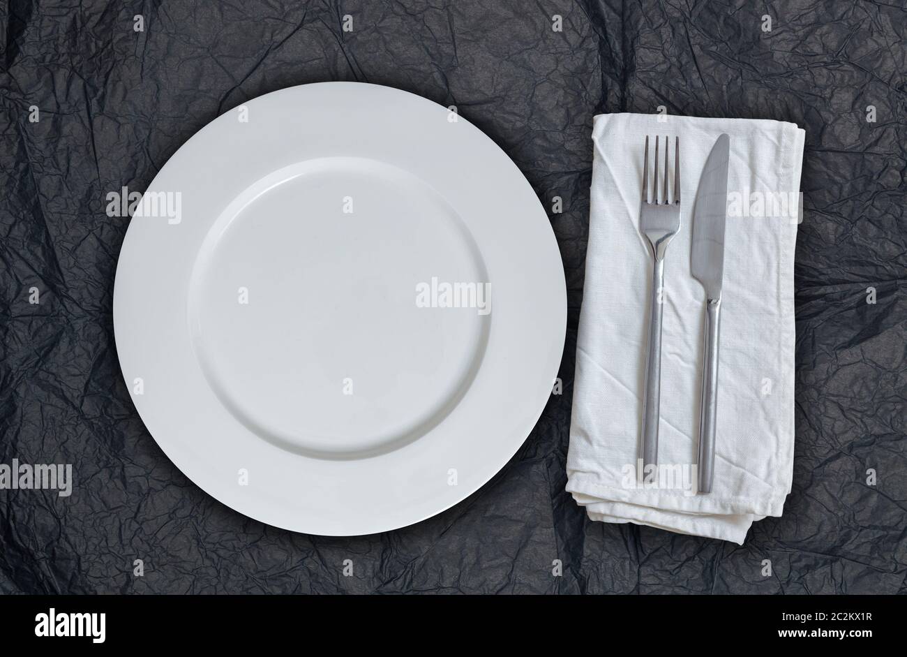 Empty plate and cutlery on black tissue paper Stock Photo - Alamy