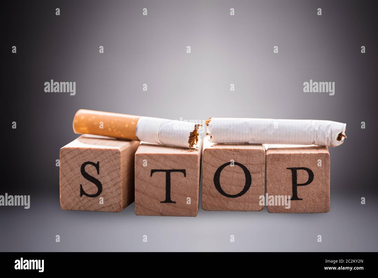 Close-up Of Broken Cigarette Over The Stop Wooden Block Against Gray ...