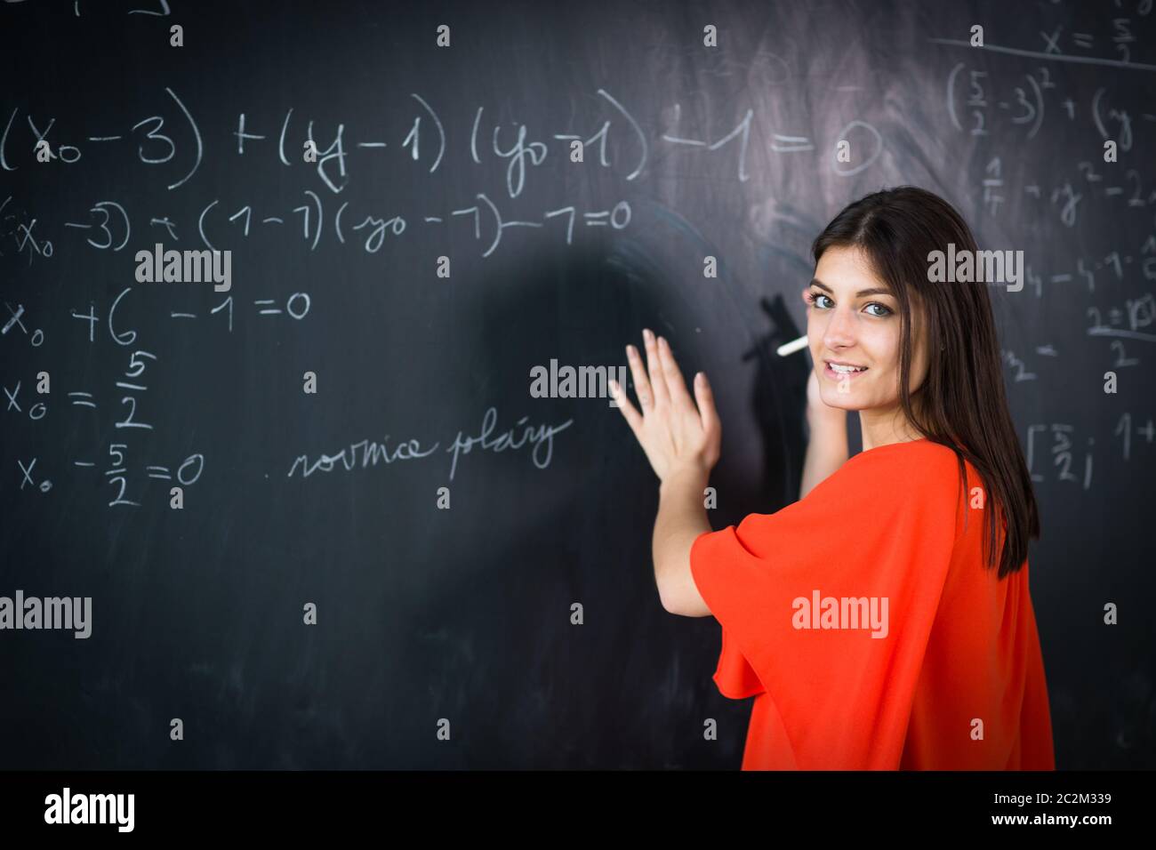 Pretty, young college student writing on the chalkboard/blackboard ...