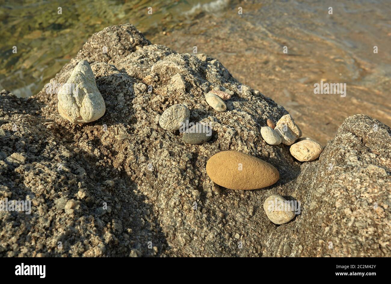 Detail of a rock with some pebbles of various colors resting on it with ...