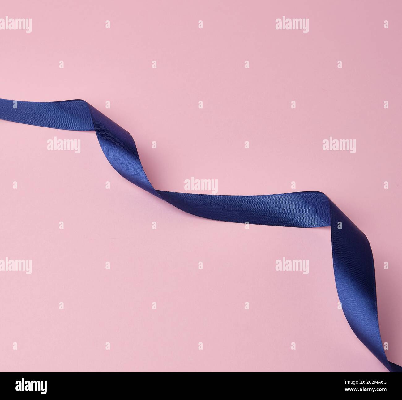 dark blue silk ribbon twisted into loops on a pink background, abstract ...