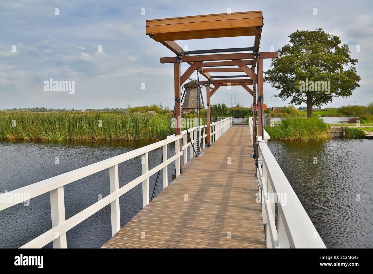 Small wooden drawbridge over a canal windmill in the background, Dutch ...