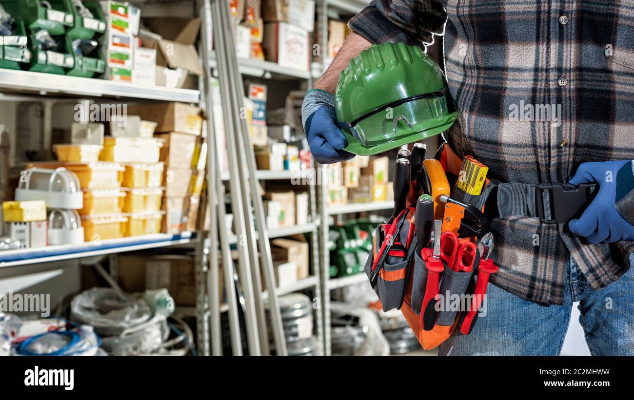 Electrician in the electrical component store wears protective gloves ...