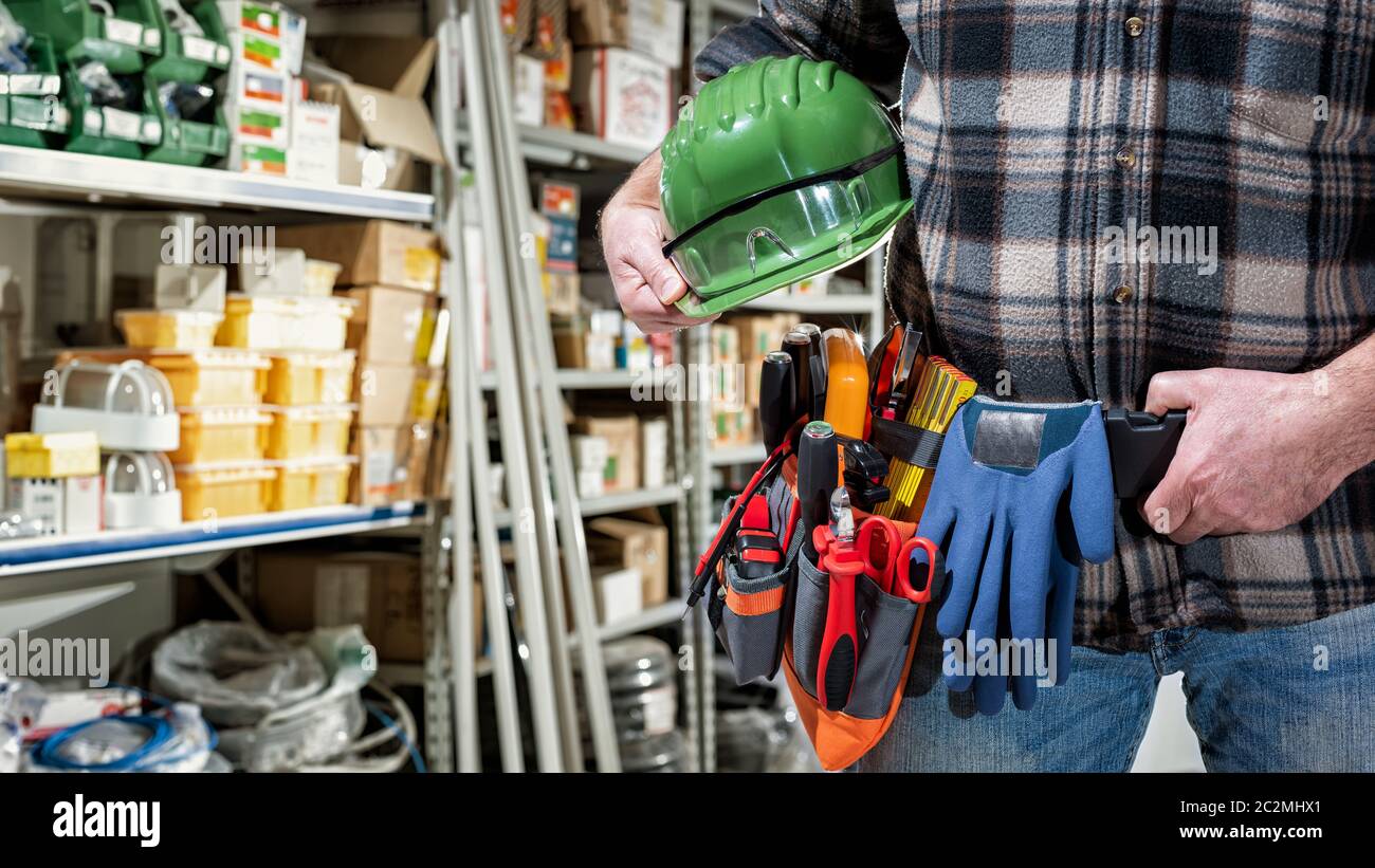 Electrician in the electrical component store holds the helmet and ...