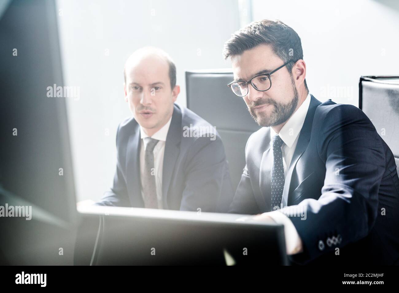 Image of two thoughtful businessmen looking at data on multiple ...