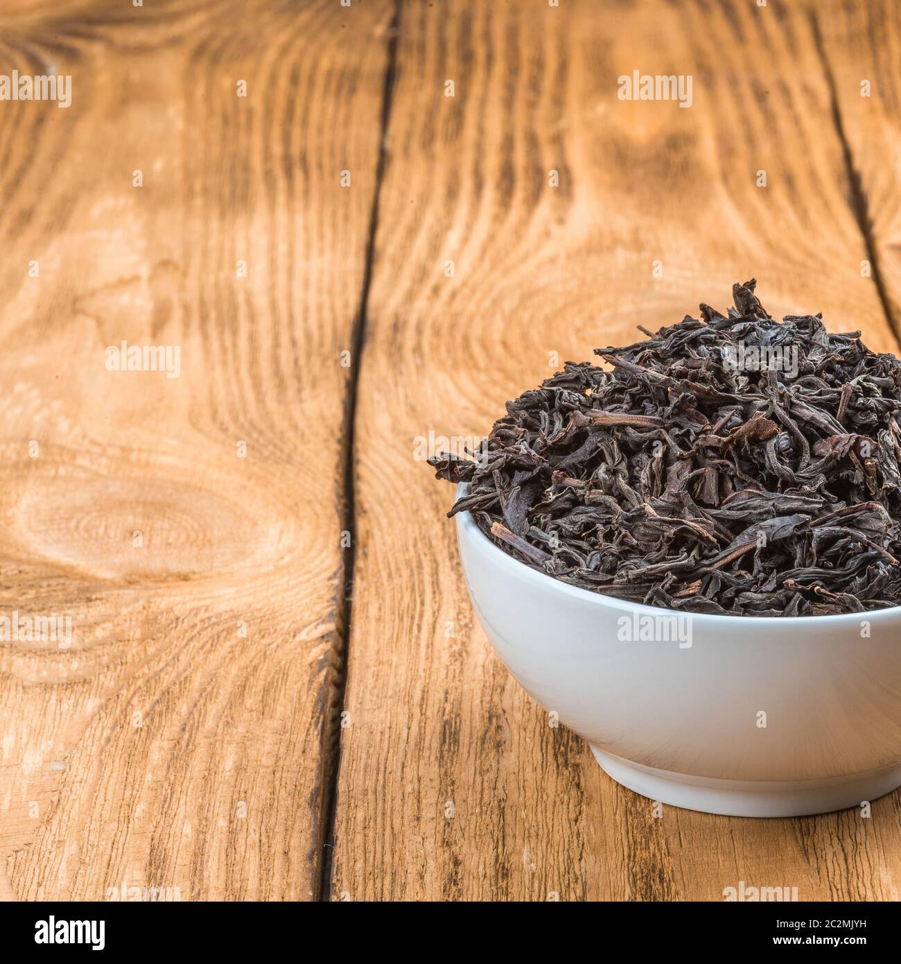 Dried tea is poured into a ceramic cup on a wooden plank table Stock ...