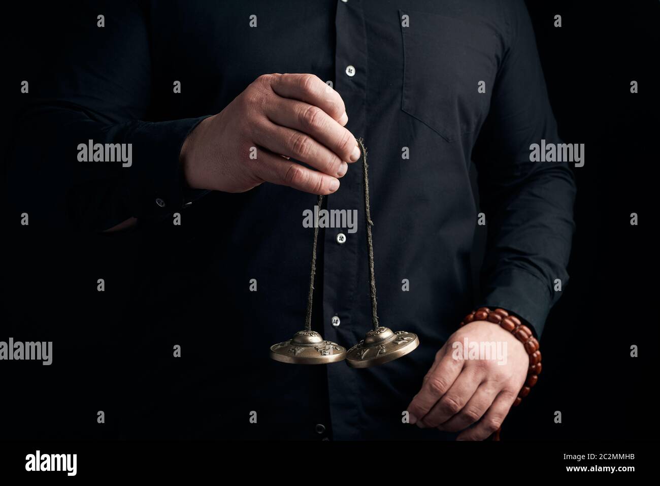 adult man in black clothes holds in his hands a pair of bronze Karatal ...