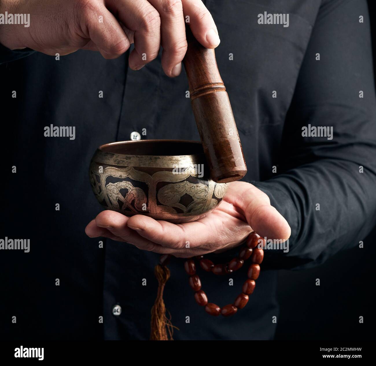 adult man in a black shirt rotates a wooden stick around a copper ...