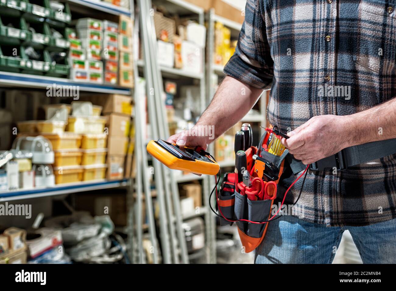 Electrician in the electrical component store holds multimeter tester ...