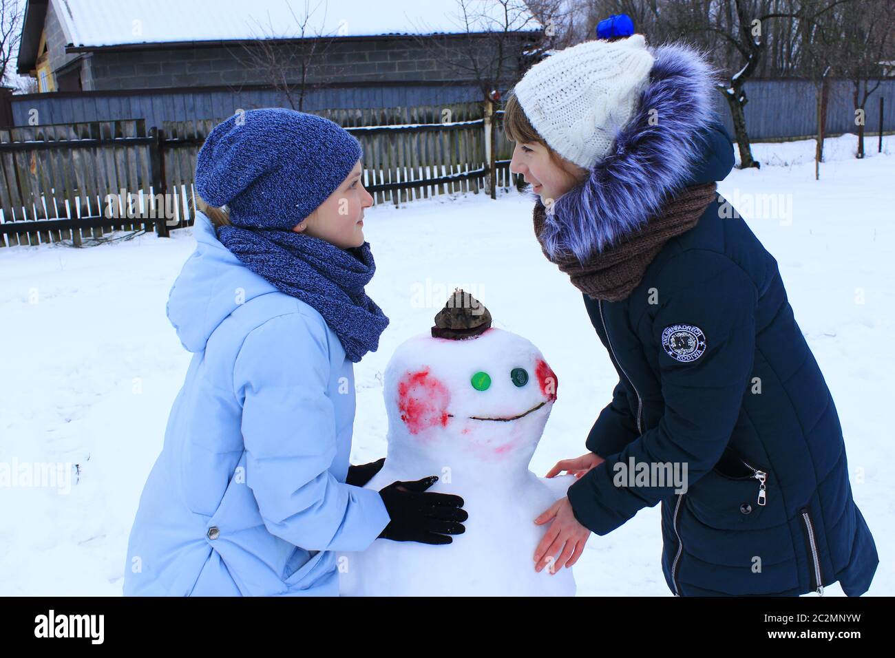 Two girls make snowman in winter. Children make snowman. Two sisters ...
