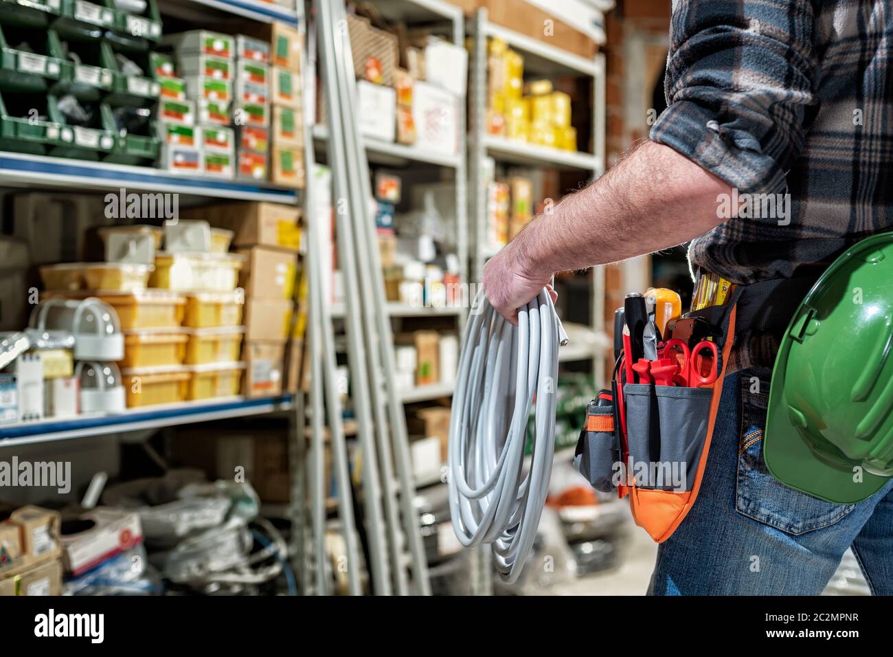 Electrician in the electrical parts store is holding the roll of ...