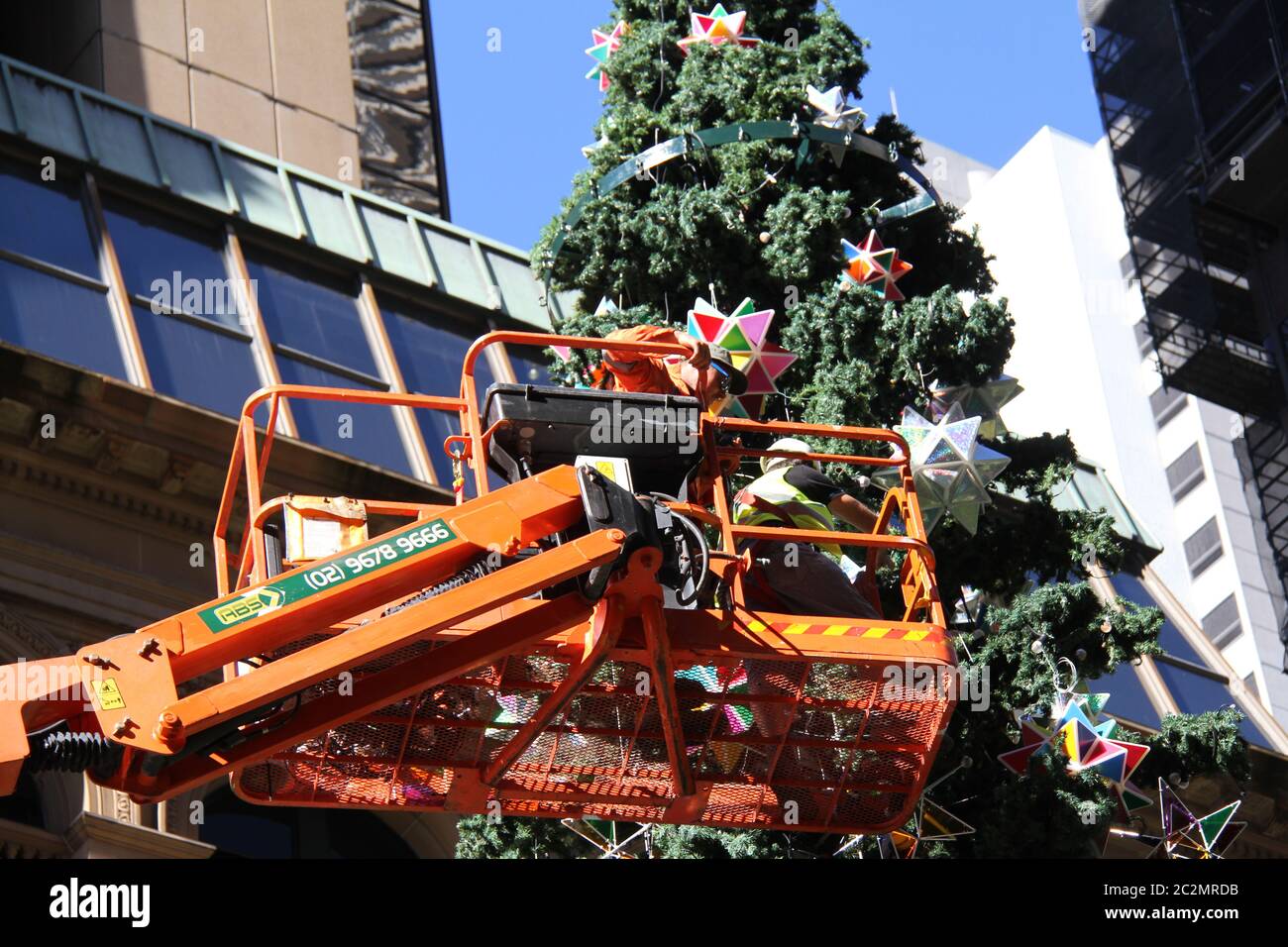Workers are lifted up in a ‘cherry-picker’ (basket crane) to attach the ...