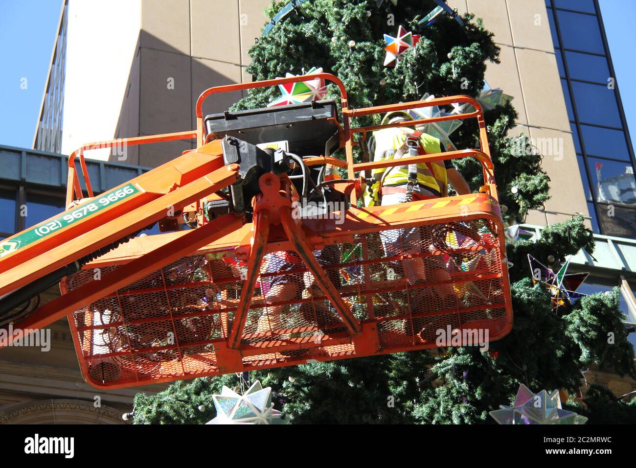 Workers are lifted up in a ‘cherry-picker’ (basket crane) to attach the ...