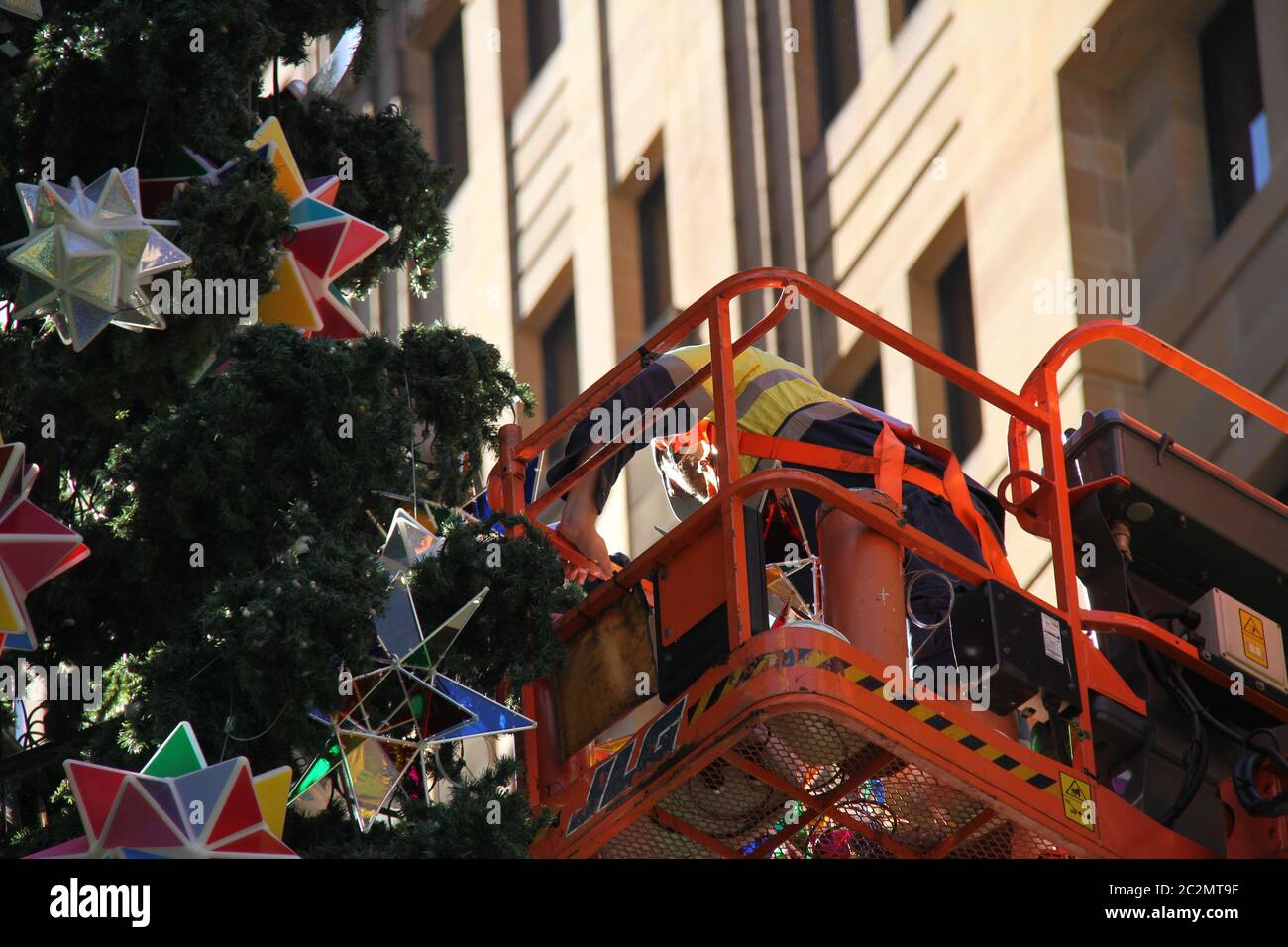 Workers are lifted up in a ‘cherry-picker’ (basket crane) to attach the ...