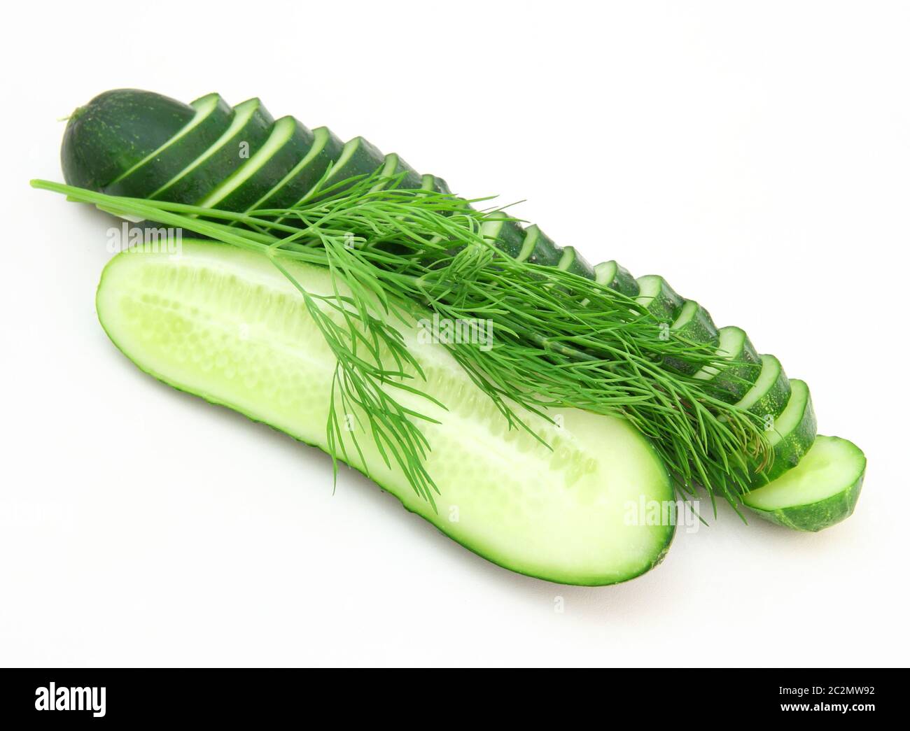 a cucumber with the cut half lying on a dill Stock Photo - Alamy