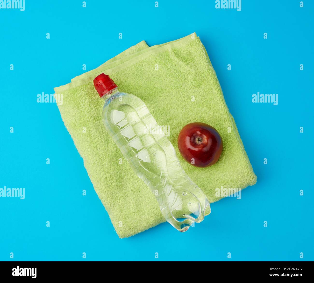 folded green terry towel and a transparent bottle of water on a blue ...