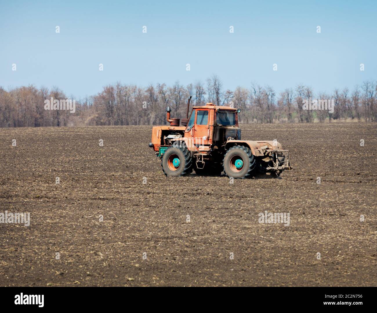 In field is moving an old tractor Stock Photo - Alamy