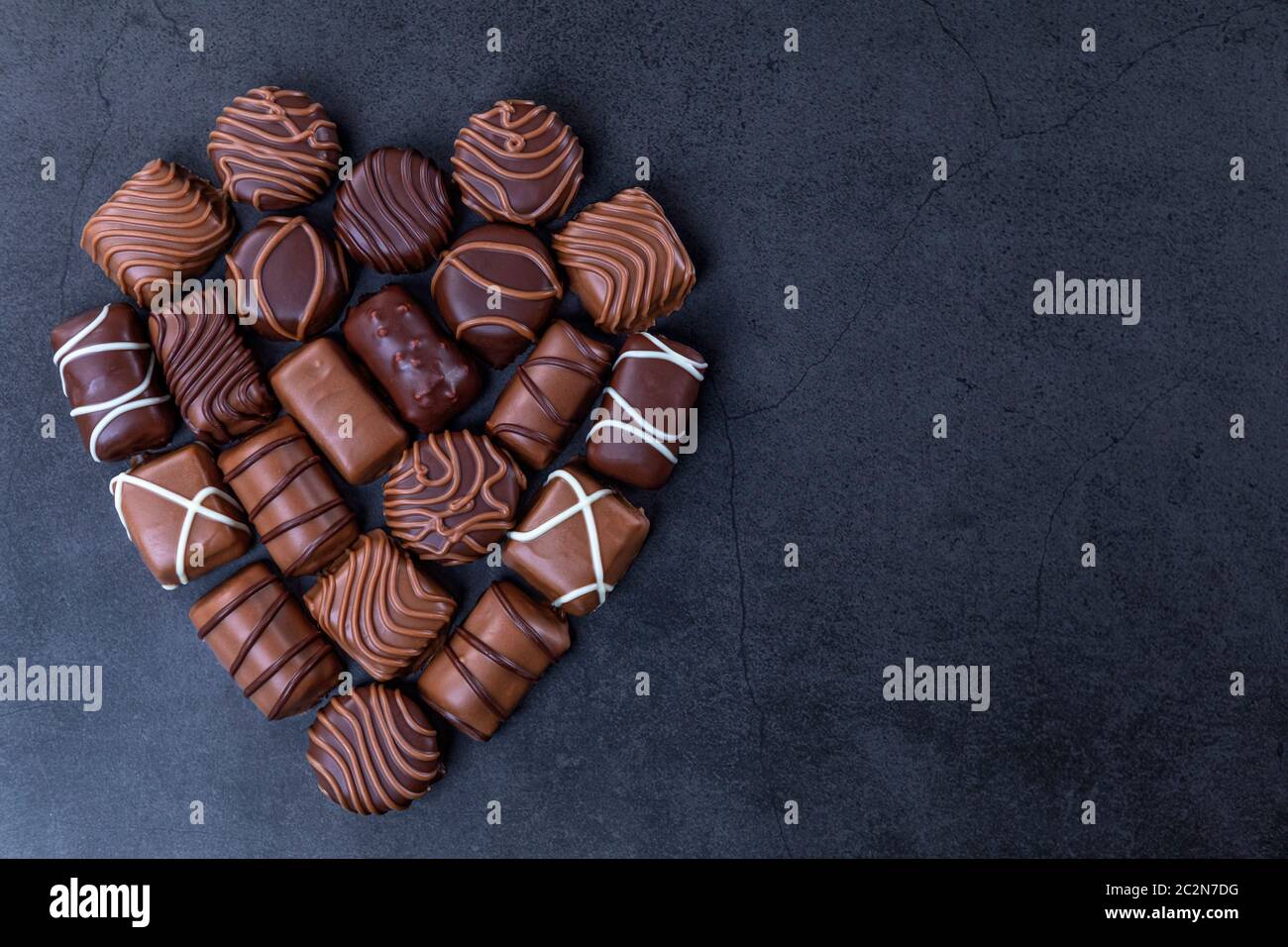 Stack of Chocolate candy in the shape of heart on a black background ...