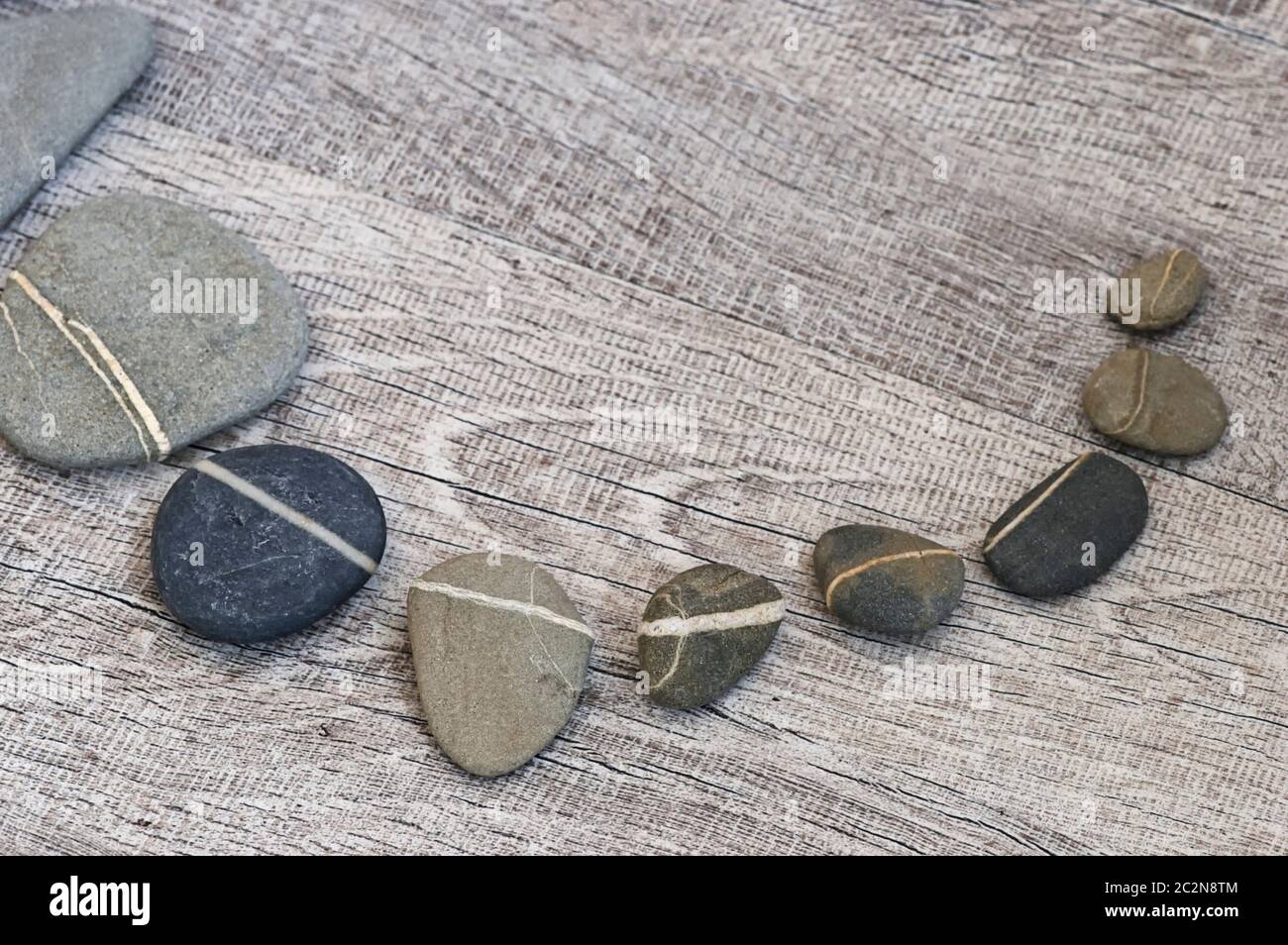 close up of smooth grey pebble with a white line, arranged in a bow ...