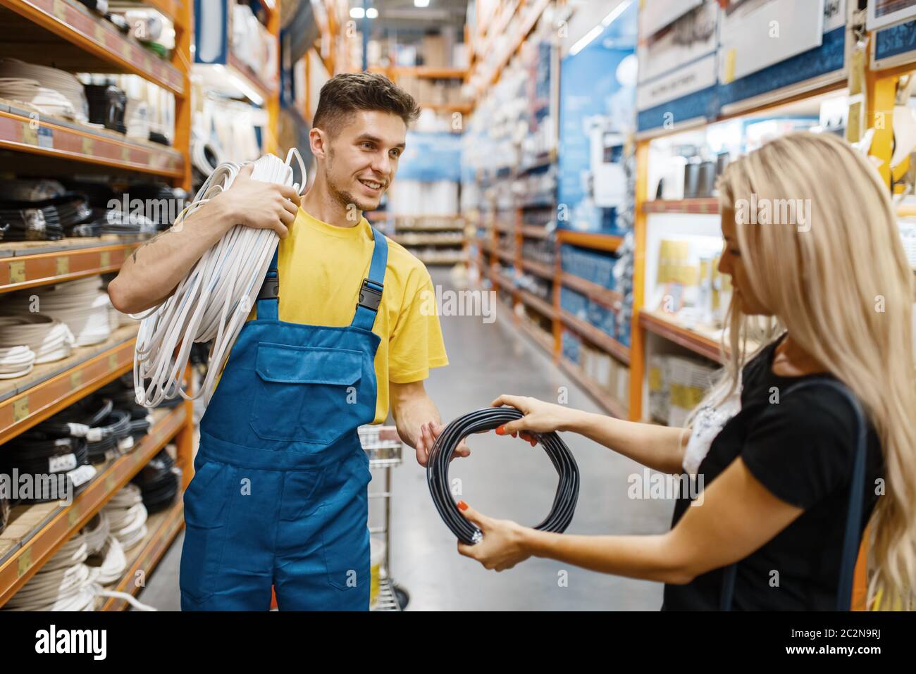 Assistant and female customer with wires in hardware store. Seller in ...