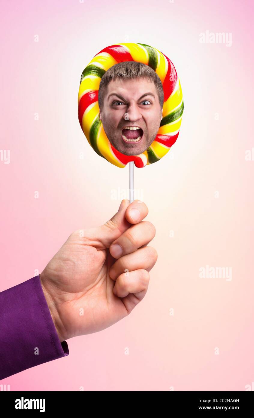 Male hand holding a lollipop with male face in it Stock Photo - Alamy