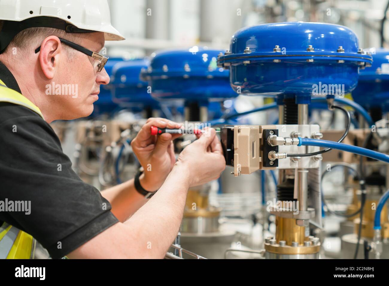 an engineer checks an pneumatic valve with a screwdriver Stock Photo ...