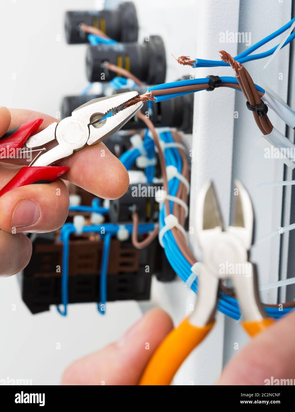 Hand of an electrician with tools at an electrical switchgear cabinet ...