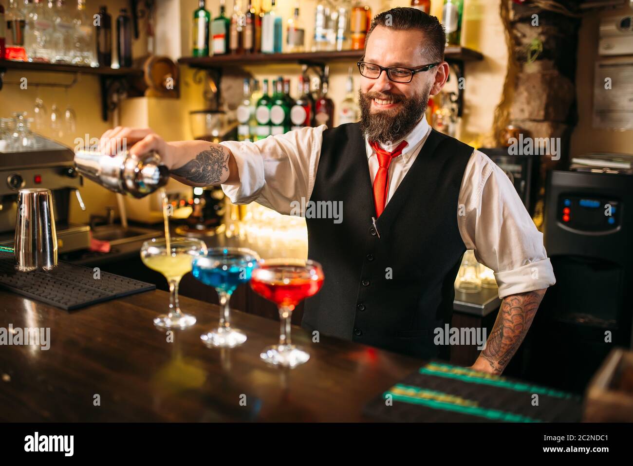Bartender with shaker making alcohol beverages behind a bar counter in ...