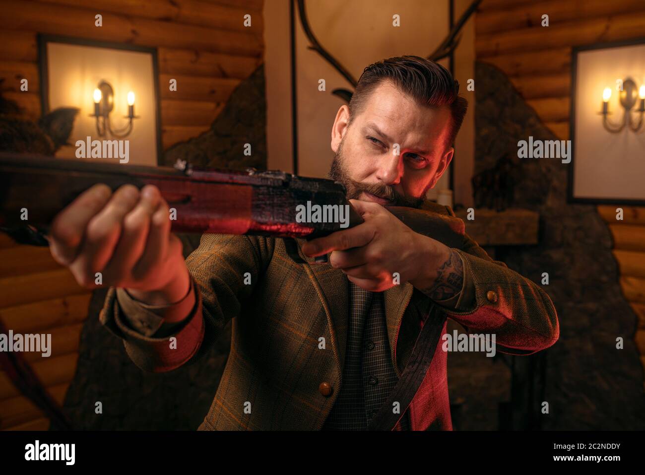 Hunter man aims of the antique hunting rifle. Fireplace, stuffed wild ...