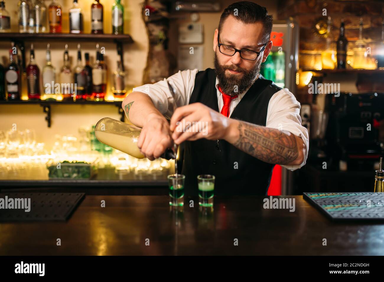 Barkeeper pouring alcoholic beverage in glass behind restaurant bar ...