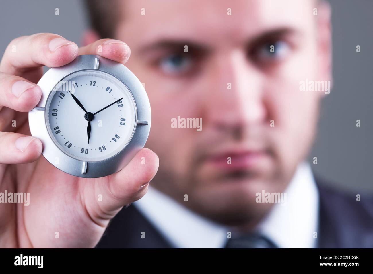 Adult serious businessman shows a little white clock Stock Photo - Alamy
