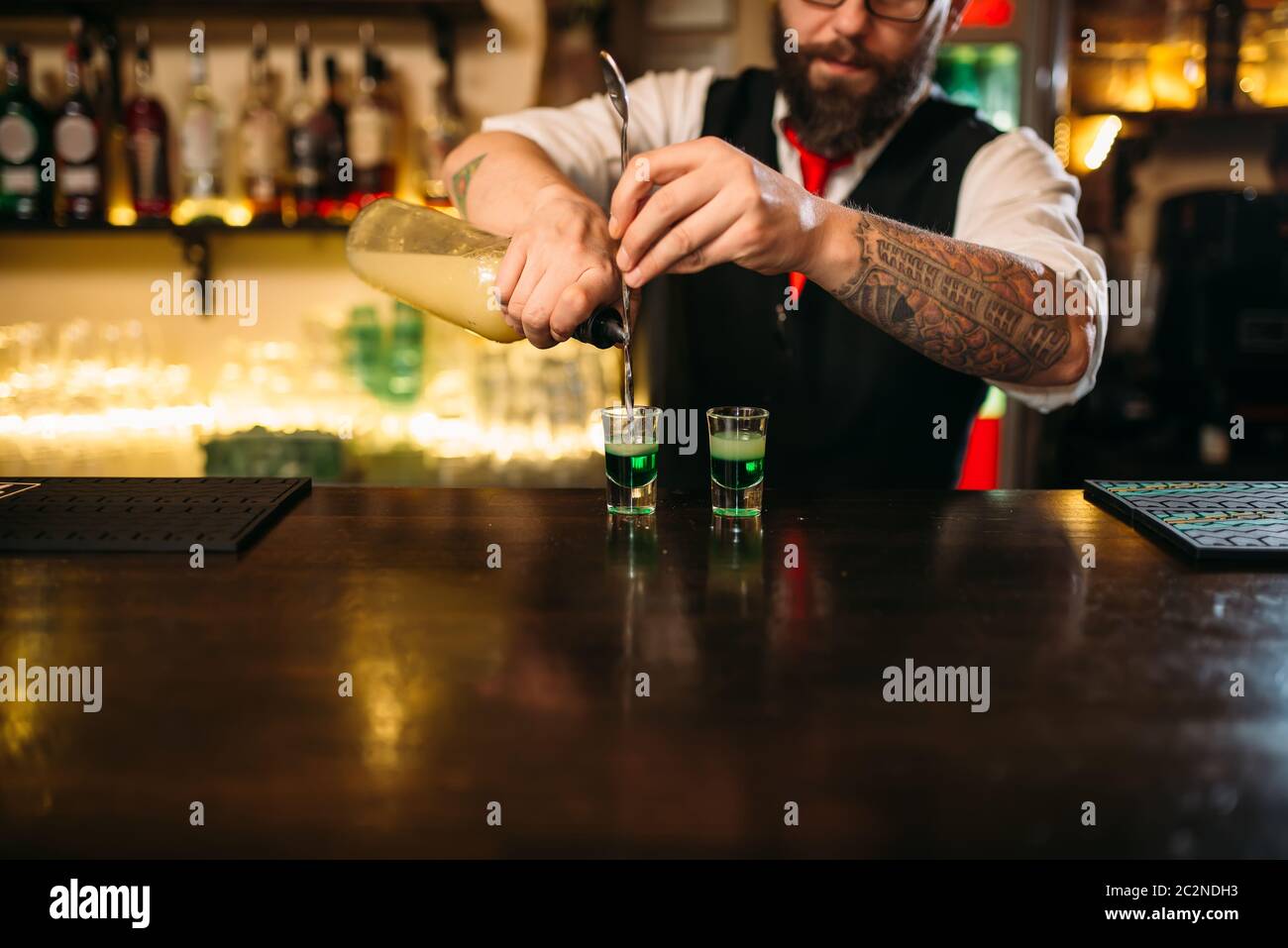 Barkeeper pouring alcoholic beverage in glass behind restaurant bar ...