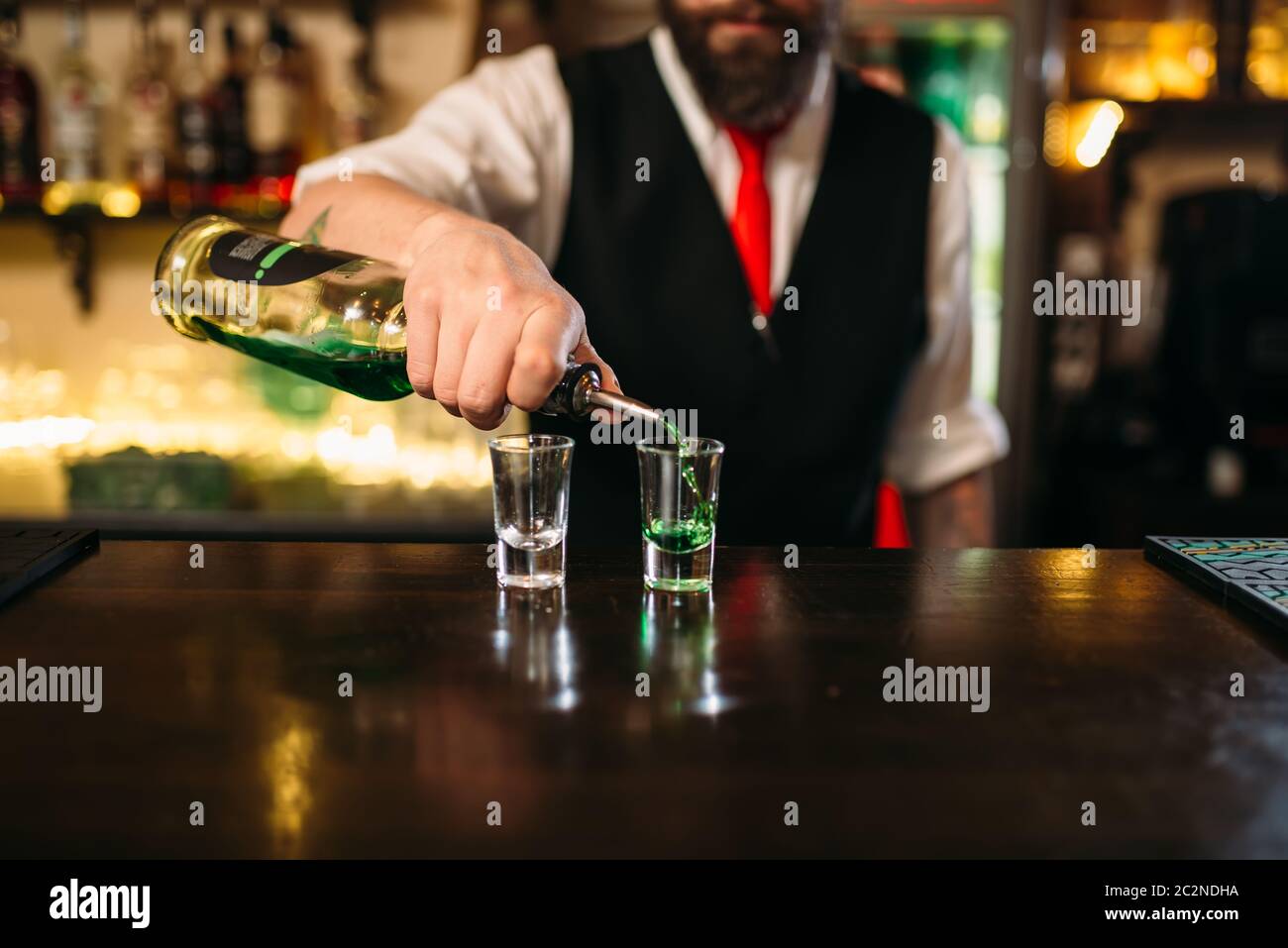 Barkeeper pouring alcoholic beverage in glass behind restaurant bar ...