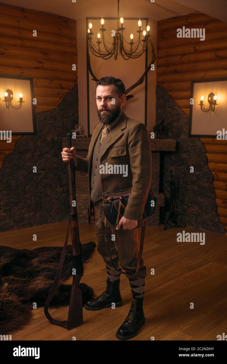 Solid hunter man in old-fashioned hunting clothing with antique gun ...
