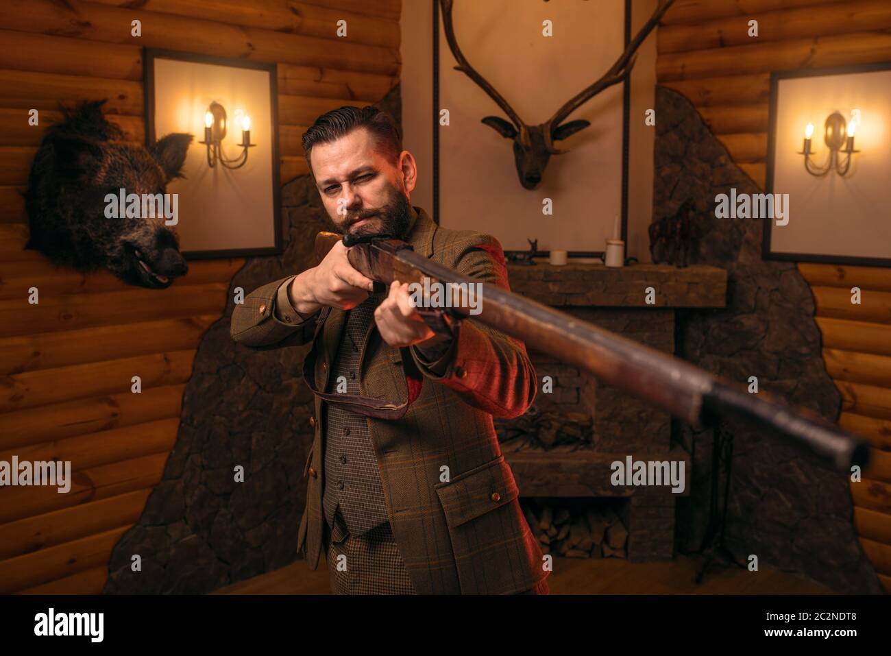 Hunter man aims of the antique hunting rifle. Fireplace, stuffed wild ...