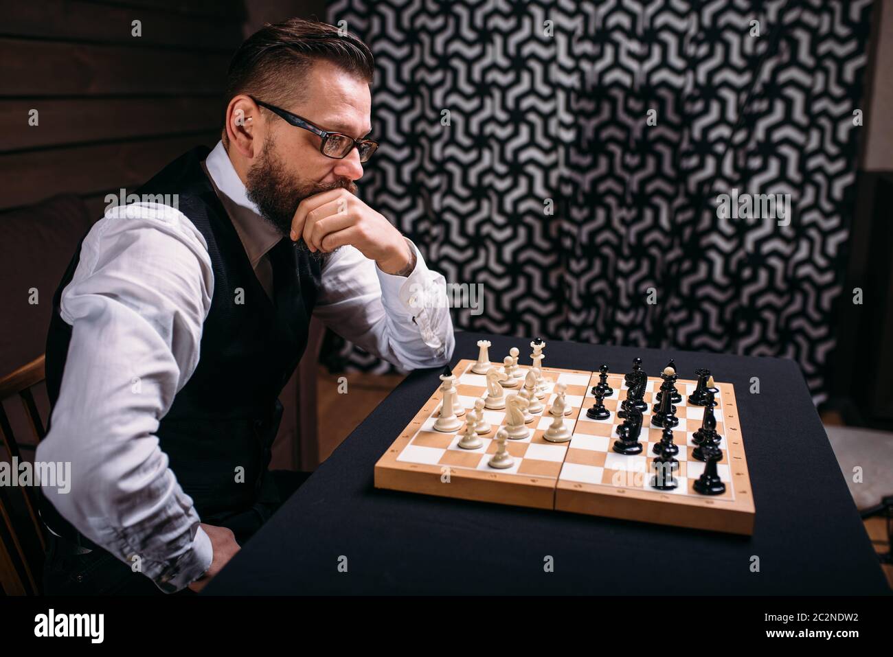 Pensive male chess player in glasses thinking about game strategy ...