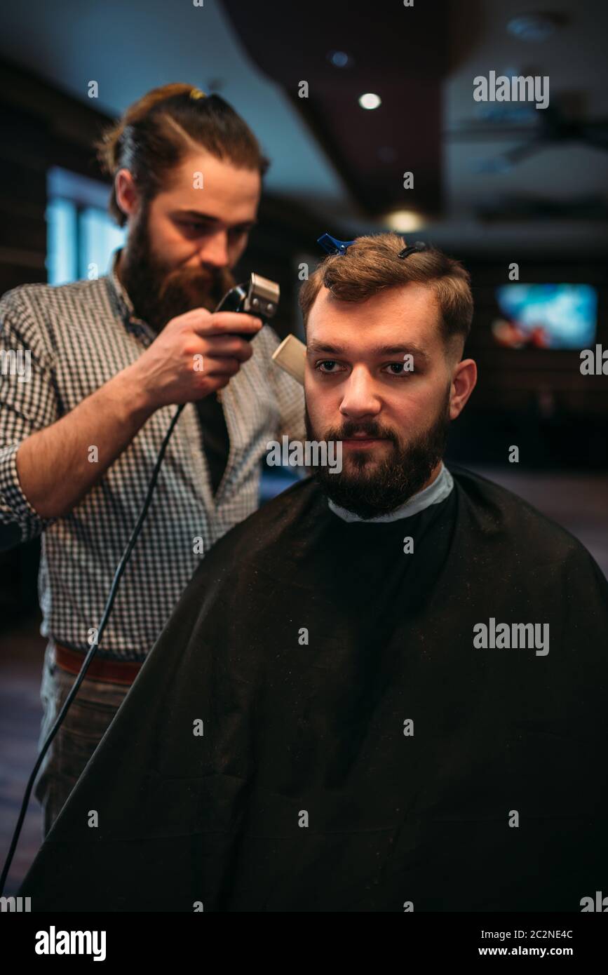 Barber working by clipper with hairstyle of the client man in black ...