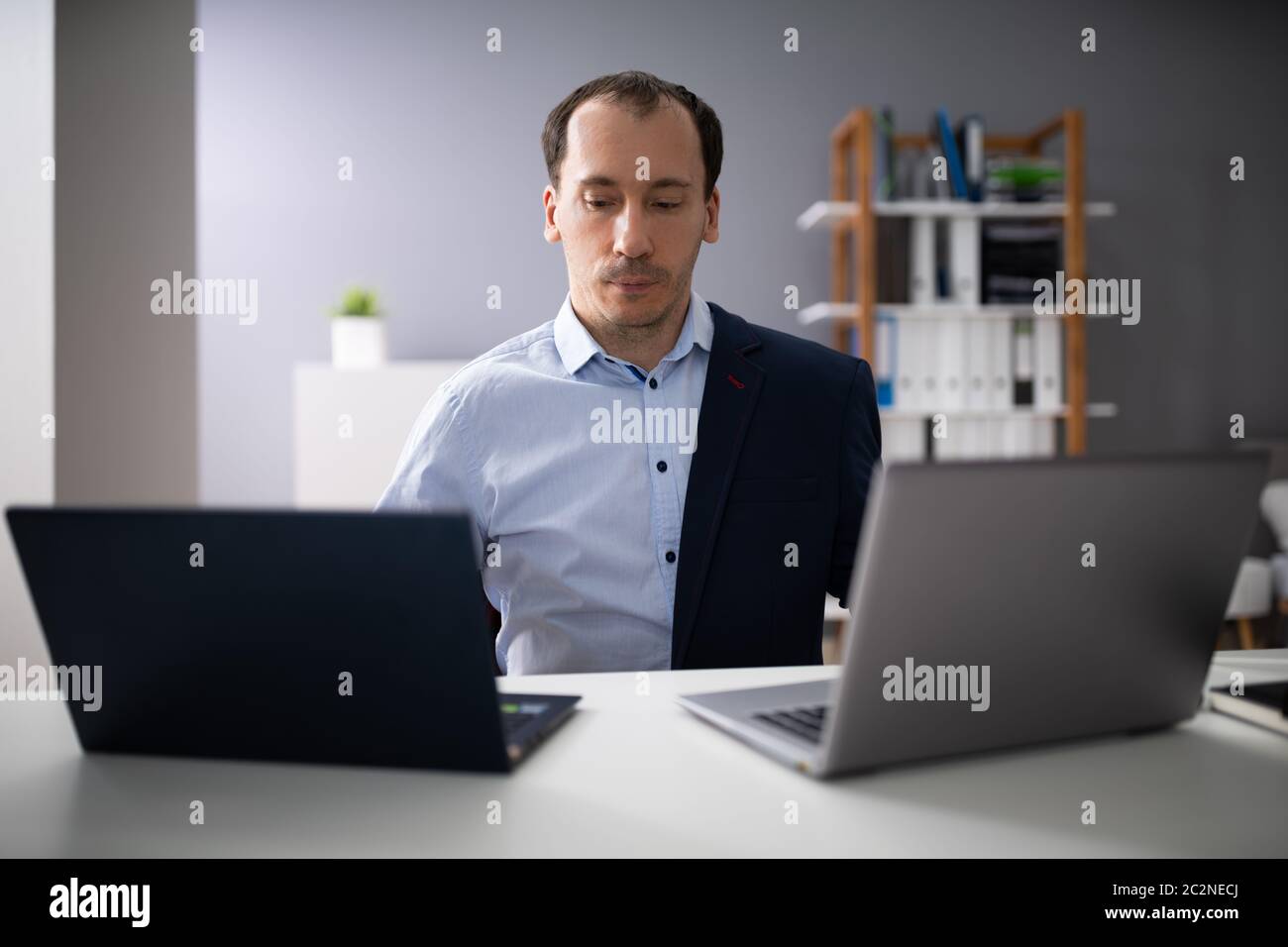 Businessperson Doing Multitasking Work On Two Laptops At Workplace ...