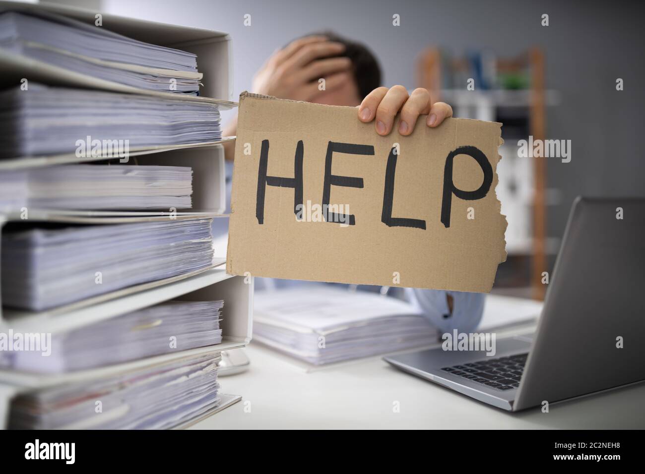 Close-up Of A Businessman Hand Holding Help Sign In Between The Stack ...
