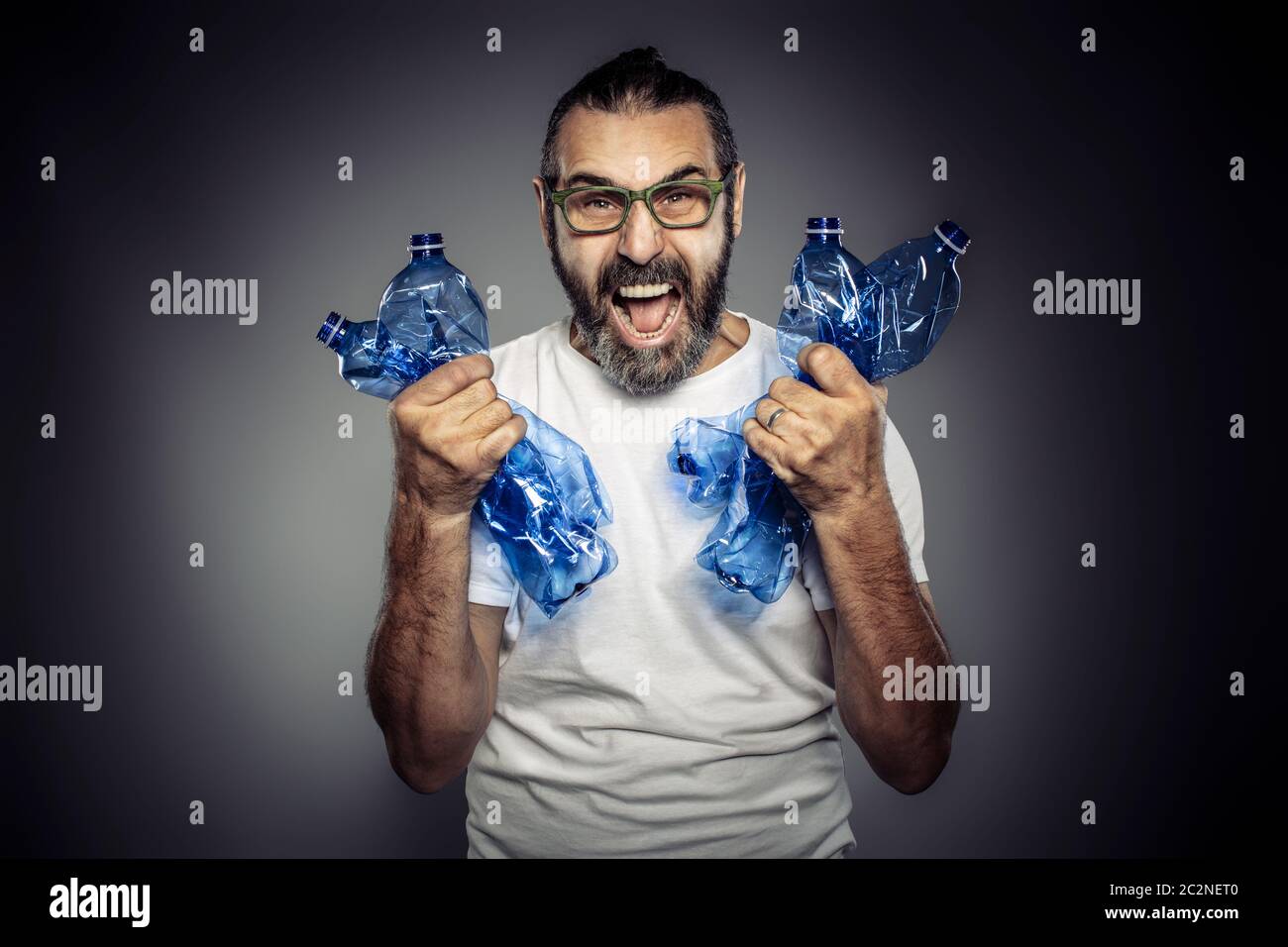 studio portrait of a man with a beard and glasses who is holding empty ...
