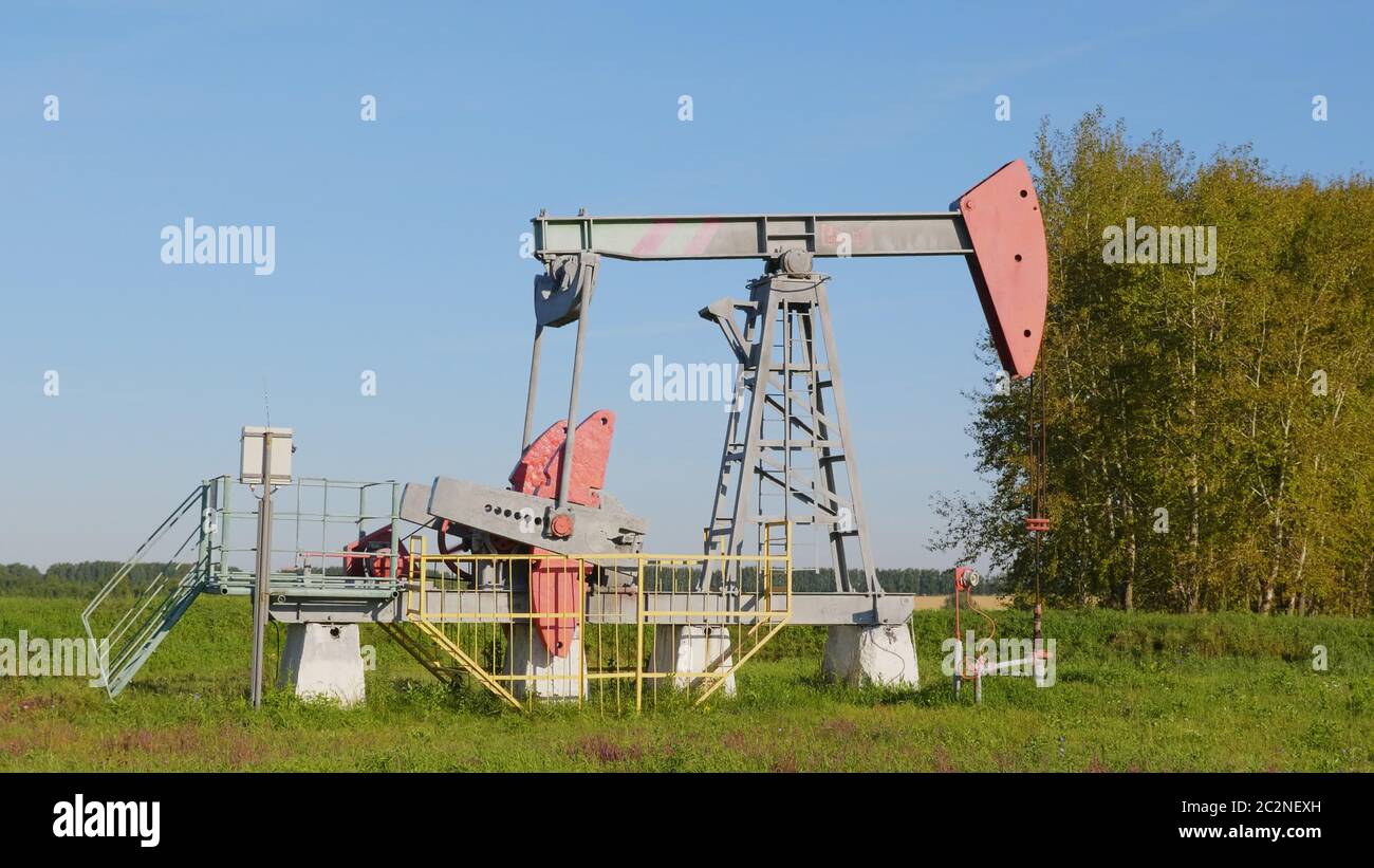 Operating oil and gas well in oil field, profiled against the blue sky ...