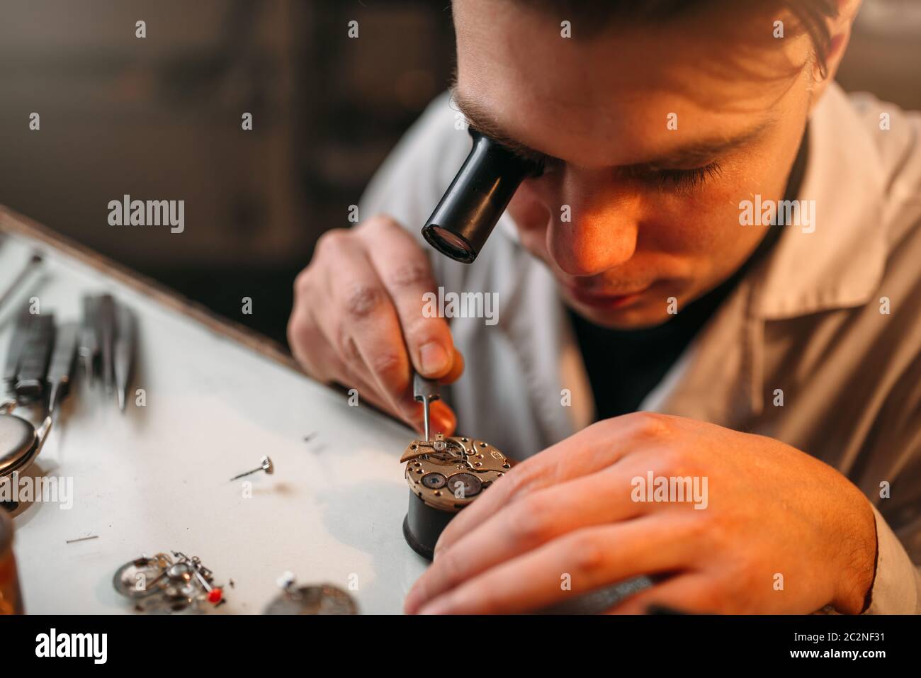 Watchmaker with loupe repair clockwork mechanism. Clock maker at work ...