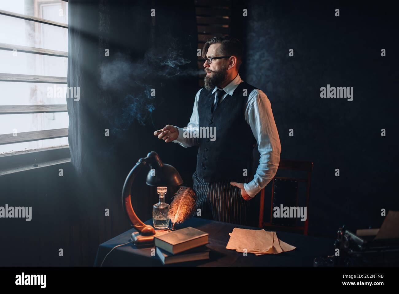 Thoughtful bearded writer in glasses smoking a cigarette and look at ...