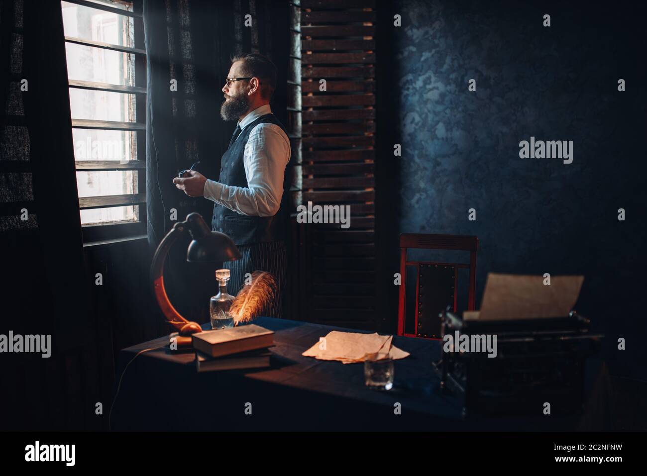Thoughtful bearded writer in glasses smoking a cigarette and look at ...