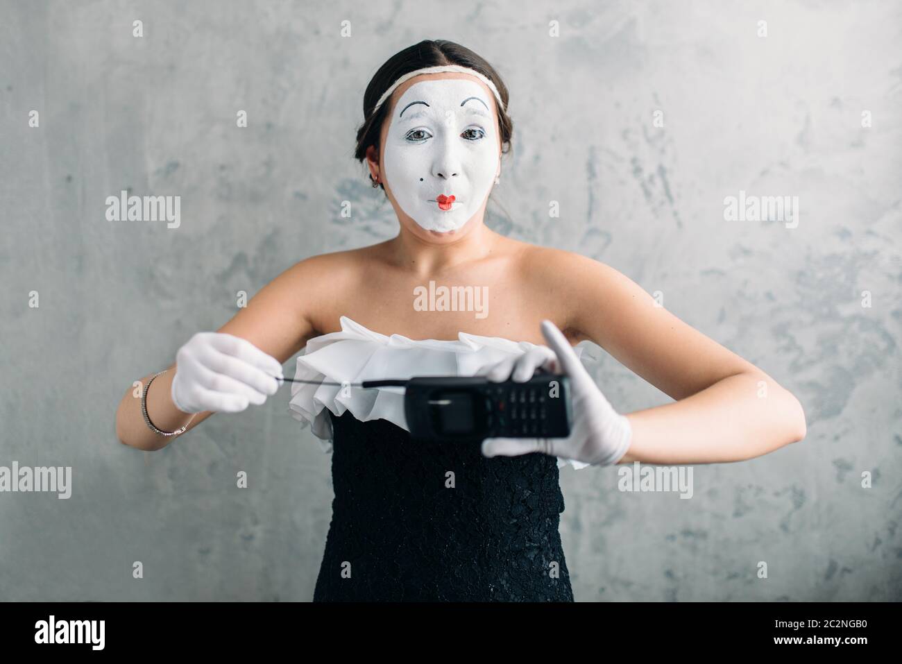 Mime female artist performing with mobile phone. Woman circus clown ...