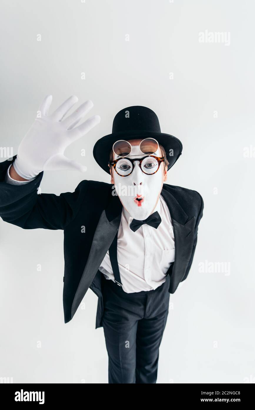 Comedy mime artist in glasses and white makeup mask. Pantomime in suit ...
