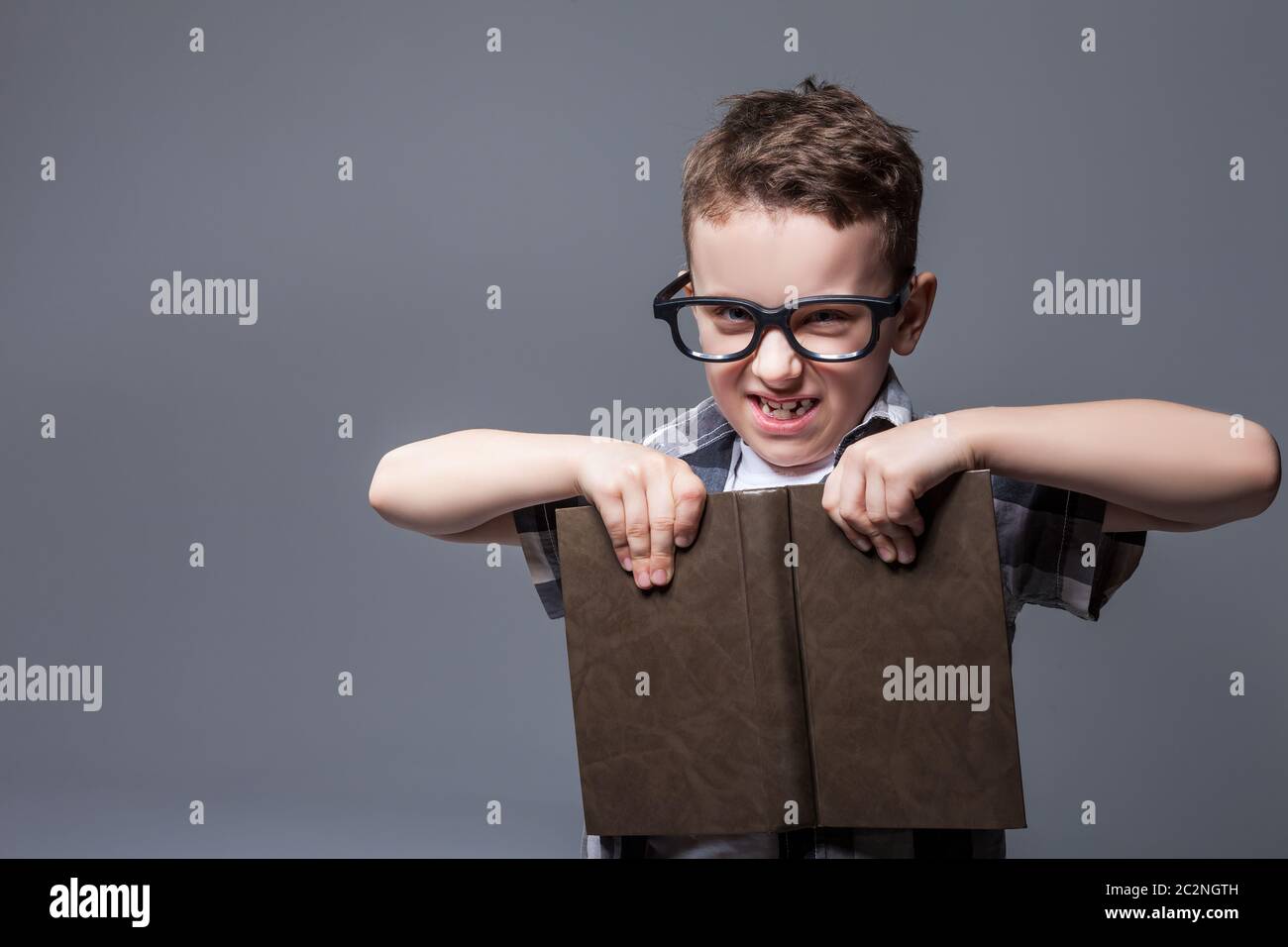 Smart pupil in glasses with textbook in hands, studio photo shoot ...