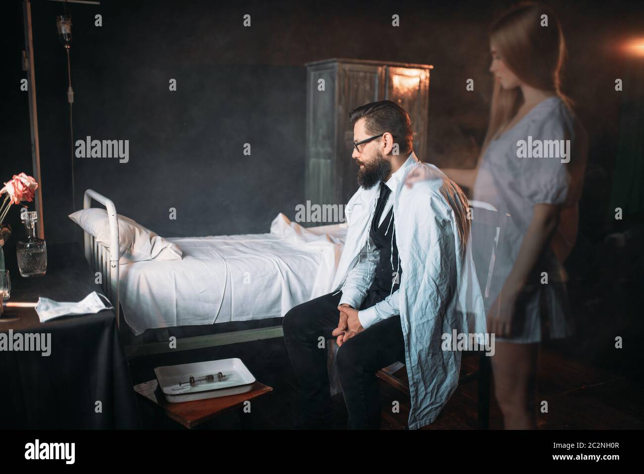 Man sitting on the chair against empty hospital bed, soul of the dead ...