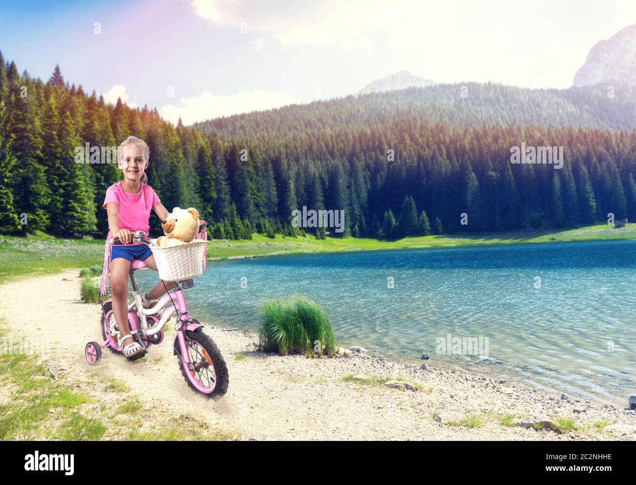 Cute little girl cycling on pink bike near the lake Stock Photo - Alamy